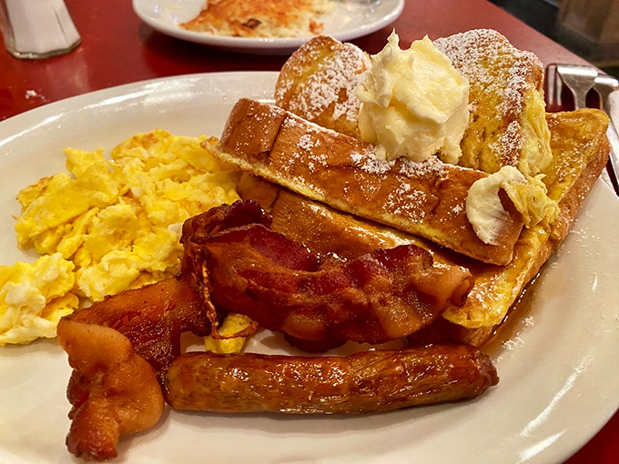 French toast nirvana achieved! Golden-brown perfection topped with a cloud of butter, crispy bacon, and eggs that would make any chicken proud.