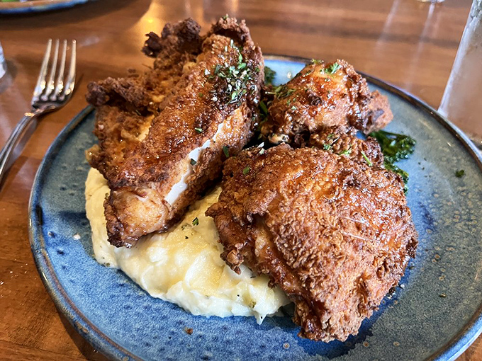 Behold the star attraction: fried chicken with a golden crust that practically auditions for its own Broadway show. Perched atop creamy mashed potatoes, it's comfort food elevated to art form.