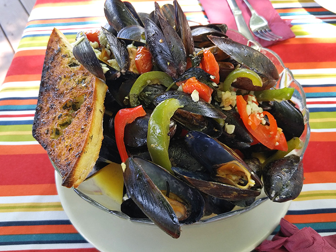 These aren't just mussels&mdash;they're little black submarines of joy navigating through a sea of garlicky, buttery goodness. The toasted bread? Your perfect rescue vessel.