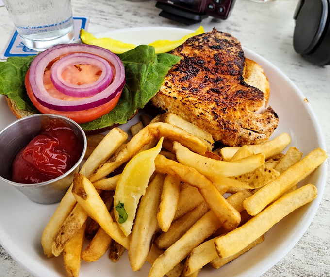 The legendary grouper sandwich in its natural habitat&mdash;perfectly blackened, nestled on a fresh bun, with a mountain of fries that demands equal attention.