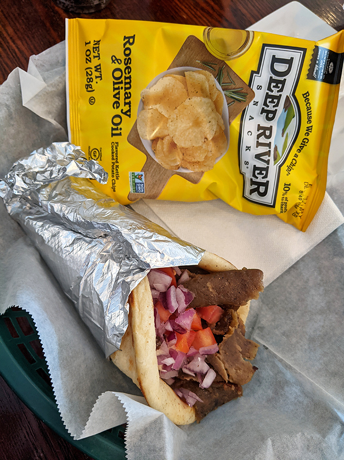 Behold the gyro in its foil-wrapped glory! Tender meat, vibrant veggies, and that tzatziki sauce that haunts your dreams long after the last bite.