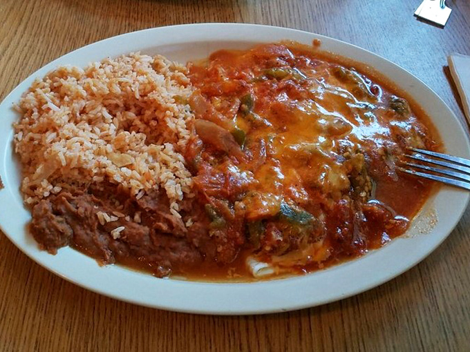Behold the enchilada plate in all its saucy glory! That vibrant ranchero sauce blankets everything in tomato-y goodness while the rice stands ready for duty.