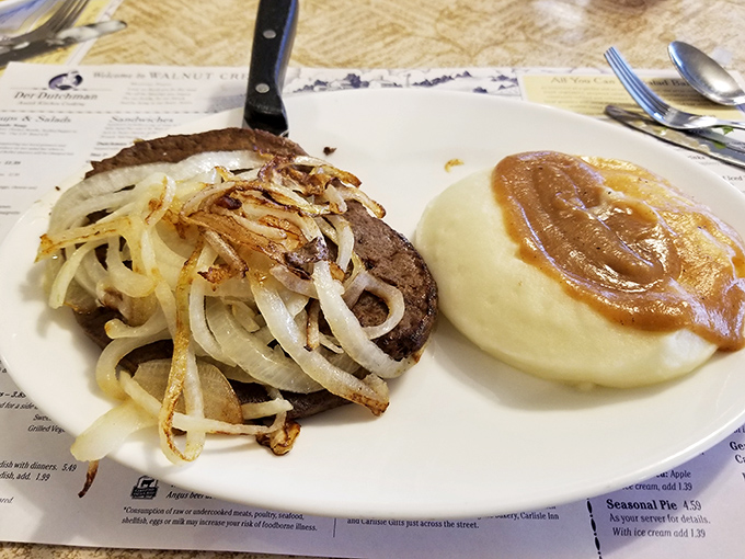 A hamburger steak crowned with caramelized onions alongside mashed potatoes swimming in gravy. This plate doesn't just feed you; it hugs you from the inside.