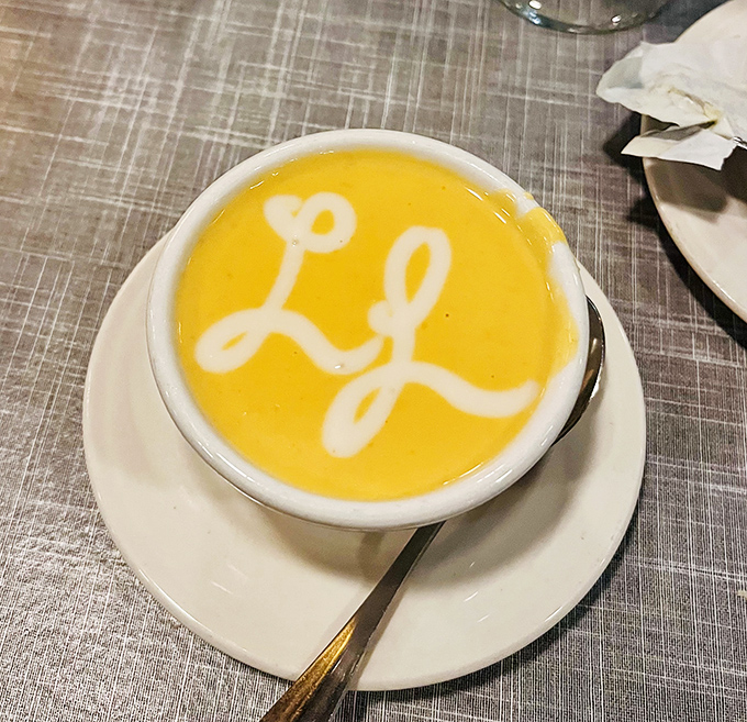 The bisque arrives with its own signature&mdash;a creamy yellow canvas where the restaurant's initials promise flavor in every spoonful.