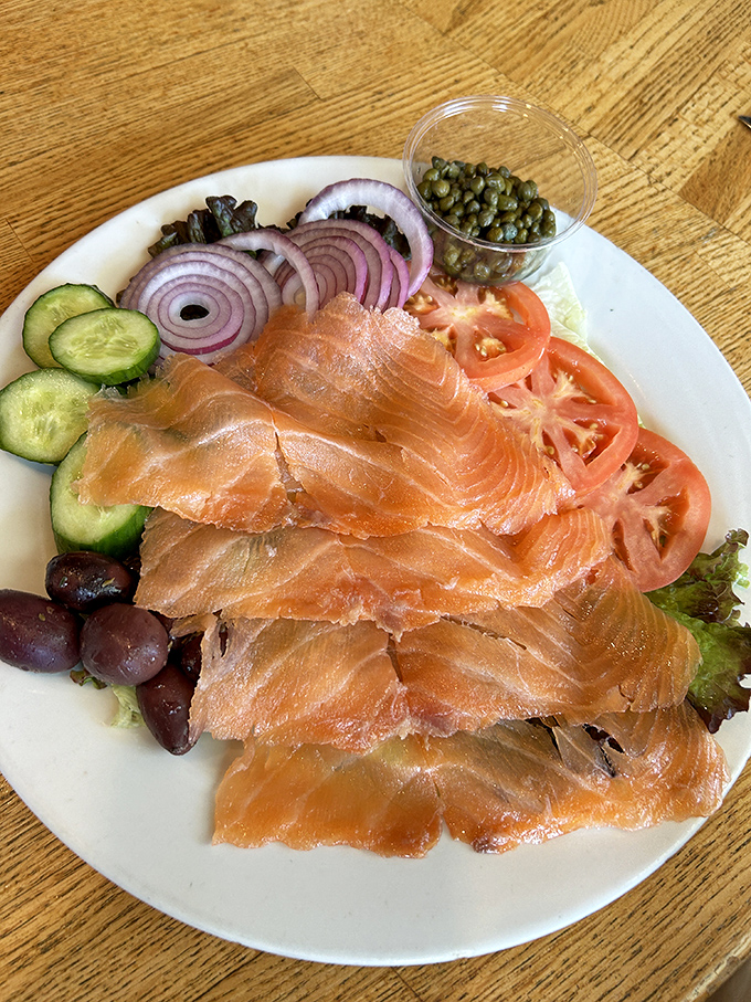 Smoked salmon arranged with artistic precision alongside capers and red onions &ndash; proof that simple ingredients handled with respect create culinary magic.