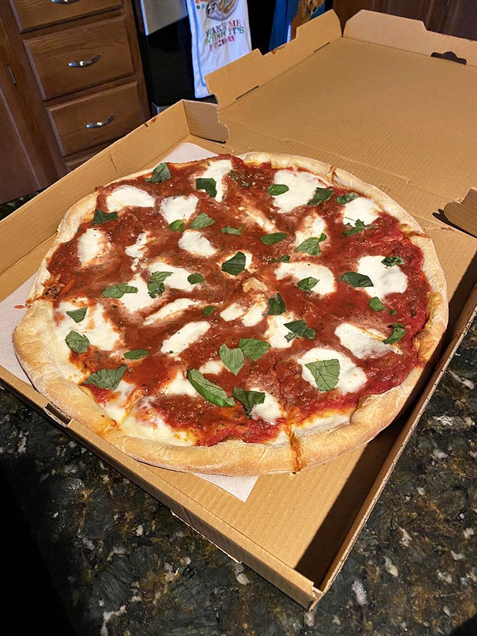 Pizza perfection in its purest form – fresh basil dancing atop pools of melted mozzarella and that sauce that haunts your dreams.