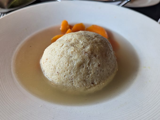 Behold the star attraction: a matzo ball that floats majestically in golden broth like the moon in a chicken-flavored sky.