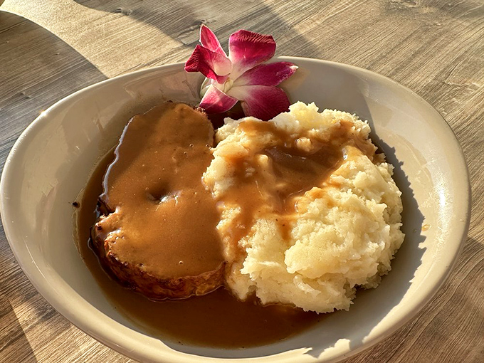 Behold the star attraction: Carol's Meatloaf with its glistening gravy lake and cloud of mashed potatoes, garnished with a tropical flower as if to say, "I'm not just dinner, I'm a vacation."