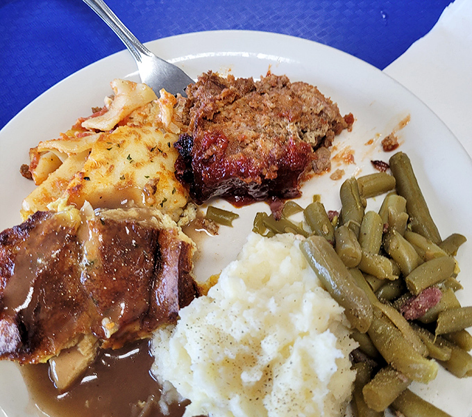 The holy trinity of comfort: meatloaf with that perfect caramelized edge, country green beans, and mashed potatoes swimming in gravy. Napkins were invented for moments like this.