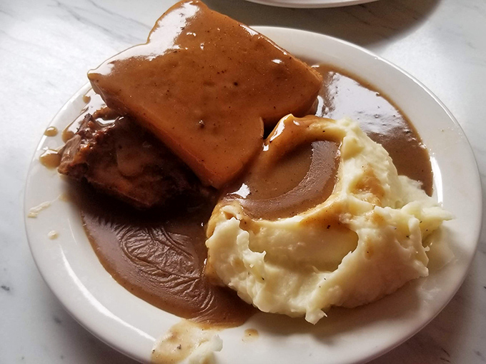Behold the star attraction: meatloaf swimming in gravy with cloud-like mashed potatoes. This isn't just food&mdash;it's a warm hug on a plate. 