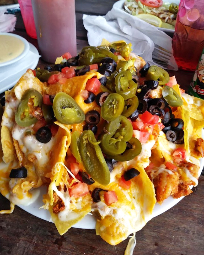 These loaded nachos aren't messing around – they've come dressed for the party with jalapeños, olives, and enough cheese to make Wisconsin nervous.