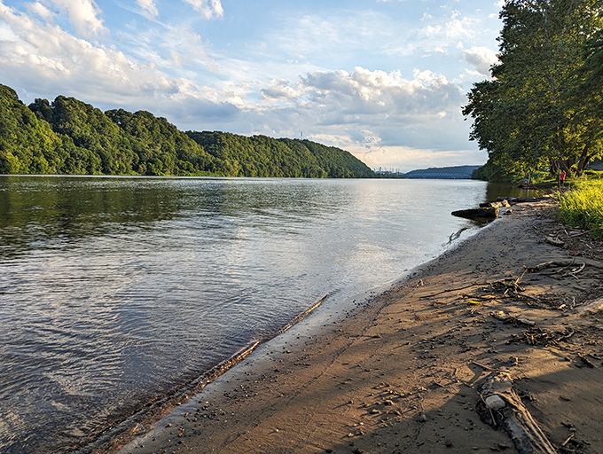 The Ohio River flows with quiet confidence past tree-lined shores, offering a peaceful retreat where water meets wilderness just steps from town.