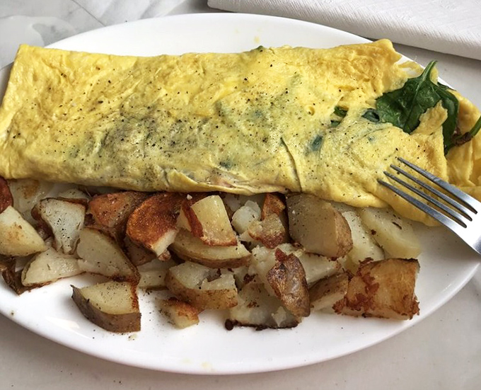 Behold the omelet in its natural habitat &ndash; fluffy, golden, and ready to make your morning spectacular. Those home fries aren't just sidekicks, they're co-stars.