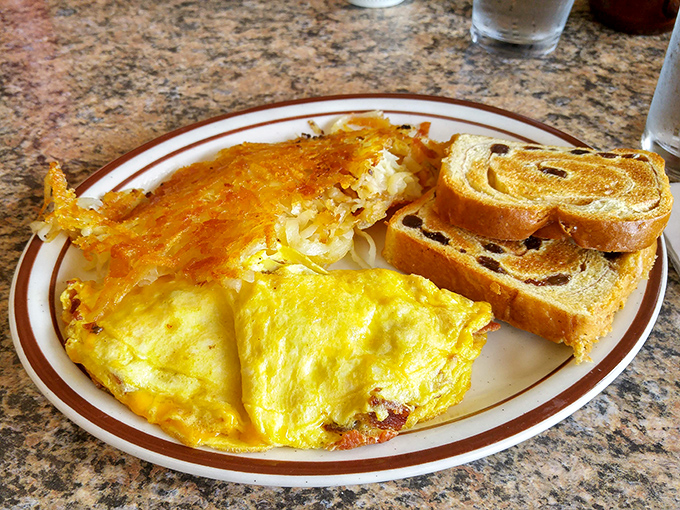 Behold the omelet in its natural habitat&mdash;perfectly executed, cheese pulling a disappearing act at the edges, with crispy hash browns standing guard.