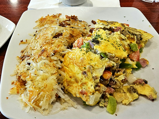 This isn't just an omelet; it's a masterpiece of morning indulgence with perfectly crispy hash browns that deserve their own fan club.