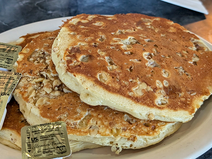 These aren't just pancakes; they're fluffy golden discs of joy with walnut confetti. The butter packets stand by, ready for their melting moment of glory.
