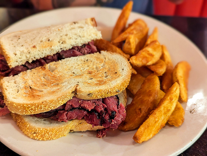 This isn't just a sandwich&mdash;it's a monument to pastrami perfection, stacked high between rye bread with golden potato wedges standing guard.