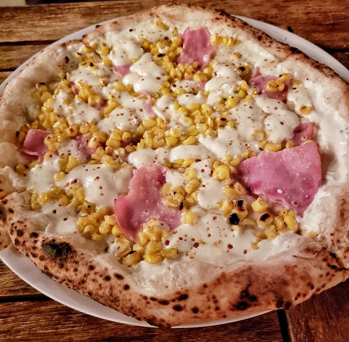 Pizza alchemy: creamy white base, pink ham, and sweet corn create a harmony that would make Mozart weep into his dough. 