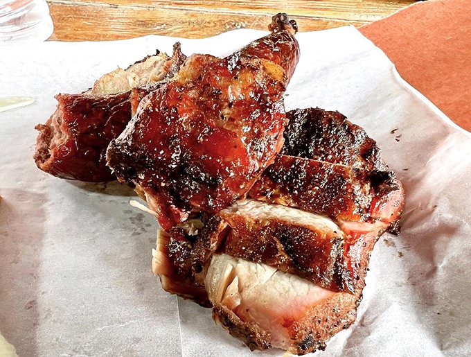 Behold the pork steak – a glistening monument to smoke and patience with a mahogany bark that should be in the Louvre of Lunch.