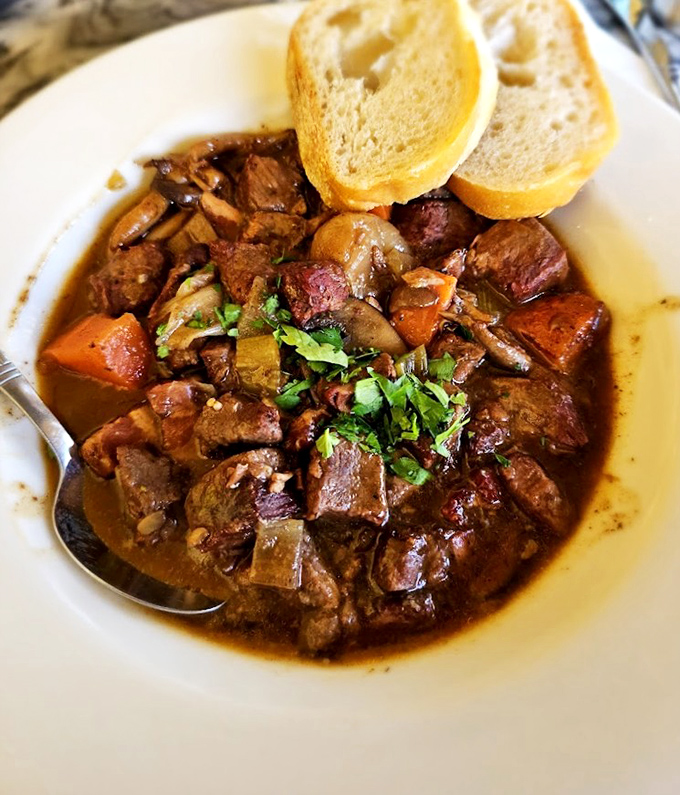 The Boeuf Bourguignon isn't just dinner&mdash;it's therapy in a bowl. Tender beef surrenders to wine-infused broth while crusty bread stands ready for sauce-sopping duty.