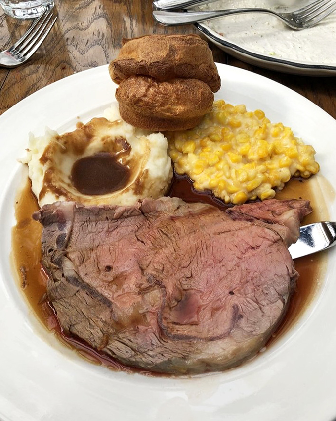 This isn't just prime rib; it's a carnivorous sunset on a plate—perfectly pink, swimming in jus, with Yorkshire pudding standing tall like a proud chef's hat.