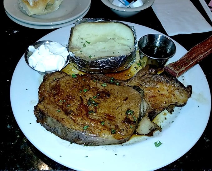 Behold the prime rib in its natural habitat—perfectly pink, accompanied by a baked potato wearing its aluminum foil tuxedo. Meat poetry on a plate.