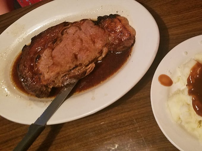 Behold the star of the show: prime rib so tender you could cut it with a stern glance, swimming in au jus that tastes like beef concentrated into liquid gold. 