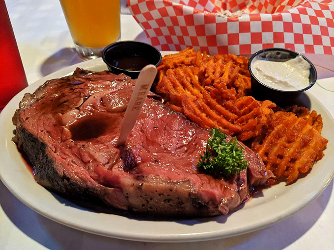 This isn't just prime rib; it's a masterpiece of meat. Perfectly pink, seasoned crust, and those waffle fries looking like they're auditioning for a food magazine cover.