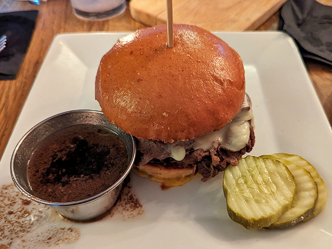 The prime rib sandwich in all its glory&mdash;tender meat, melty cheese, and that little cup of au jus waiting to elevate everything. Pickle for perspective. 
