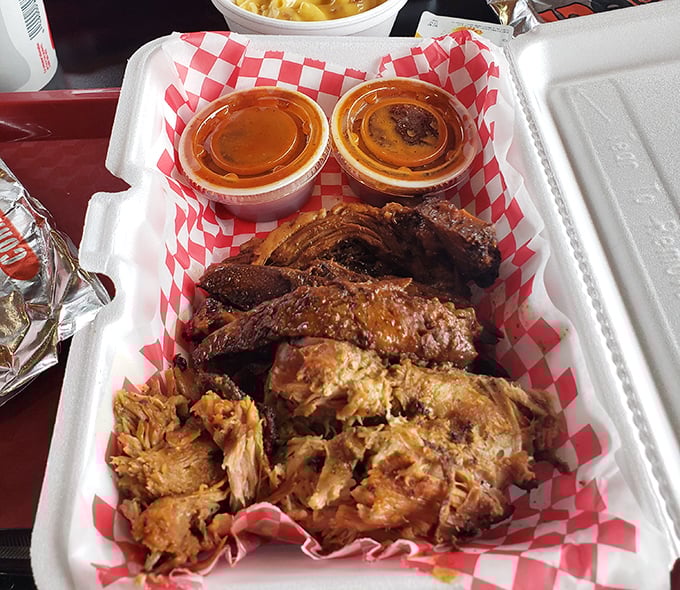 Meat poetry in a takeout container &ndash; tender pulled pork and ribs nestled together with sauce cups standing by like faithful companions.