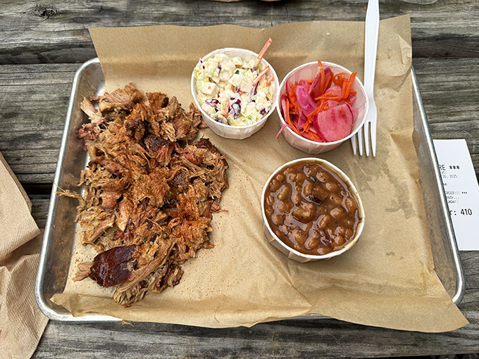Pulled pork so tender it practically surrenders to your fork, accompanied by creamy slaw, tangy pickled veggies, and beans that have clearly been simmering since the Jazz Age.