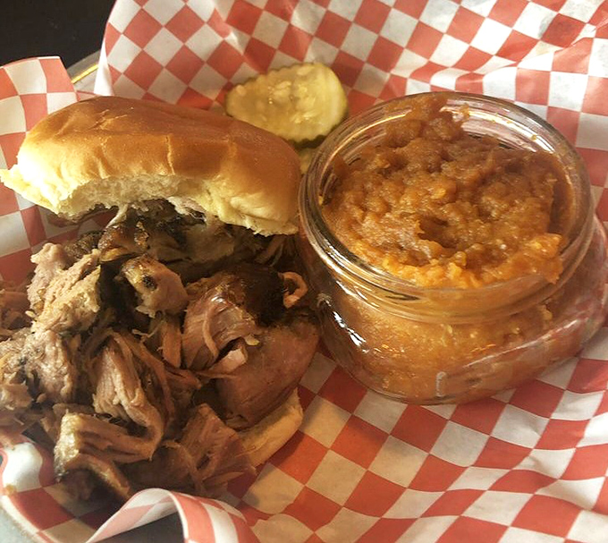 Pulled pork perfection in its natural habitat&mdash;checkered paper with a side of baked beans. This sandwich doesn't need a fancy plate to impress.