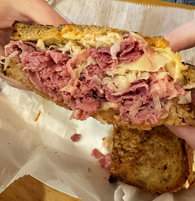 Behold the star of our show: layers of perfectly pink corned beef nestled between grilled rye. This isn't just a sandwich; it's architecture with delicious purpose.