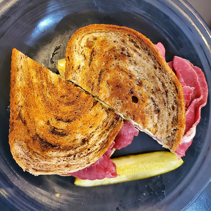 This isn't just a sandwich&mdash;it's architecture. Perfectly toasted rye, melted cheese, and that pickle standing guard like a sentry.