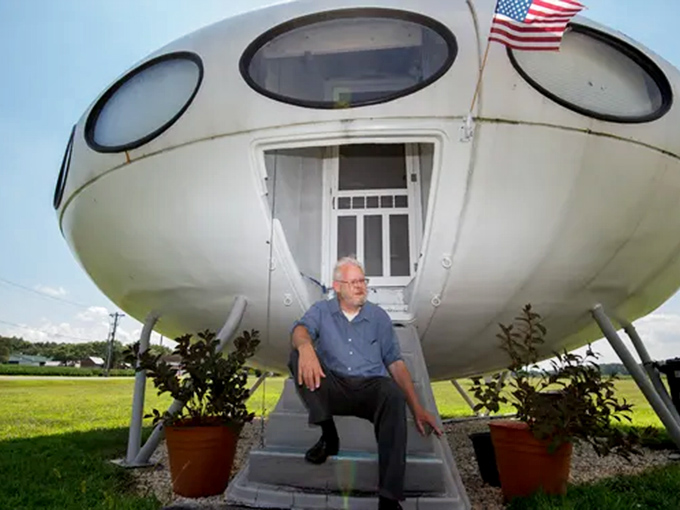 "Houston, we have a visitor." A gentleman enjoys the steps of his otherworldly dwelling, complete with patriotic flair courtesy of the American flag.