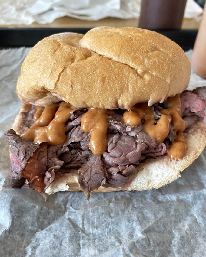 Behold the star of the show: thinly sliced roast beef piled generously on a steamed kaiser roll, with that signature sauce adding the perfect tangy kick.