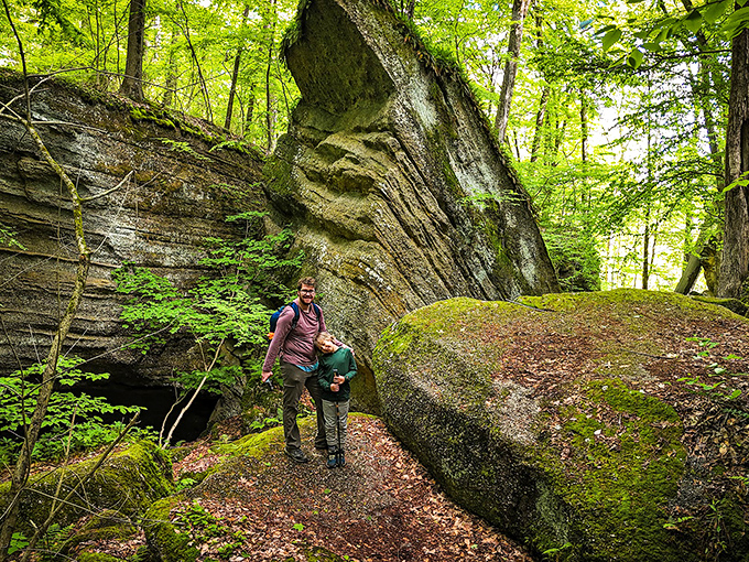 Two hikers pause beneath towering rock formations that make your garden landscaping project seem slightly less ambitious by comparison.