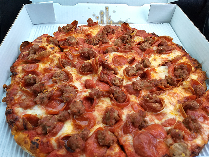 Behold the crown jewel: curled pepperoni cups creating tiny flavor pools while homemade sausage adds texture that chain pizzerias can only dream about.