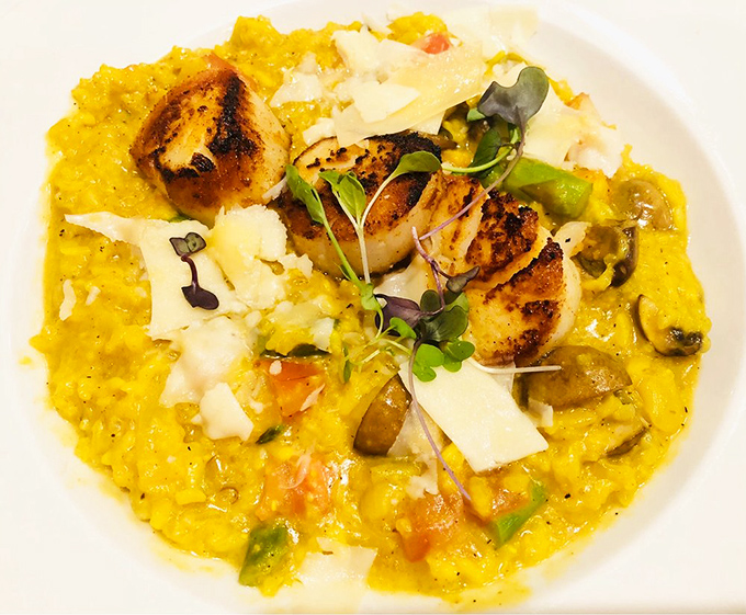 Saffron-kissed risotto cradles perfectly seared scallops like precious jewels. The microgreens aren't just garnish&mdash;they're the exclamation point on a bold statement.