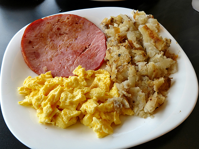 Scrambled eggs that look like fluffy yellow clouds, ham with perfect grill marks, and hash browns crispy enough to make a potato proud.
