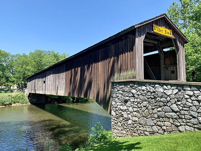 Summer sunshine transforms the bridge into a study of contrasts: dark weathered wood against crystal waters, solid stone against flowing current.