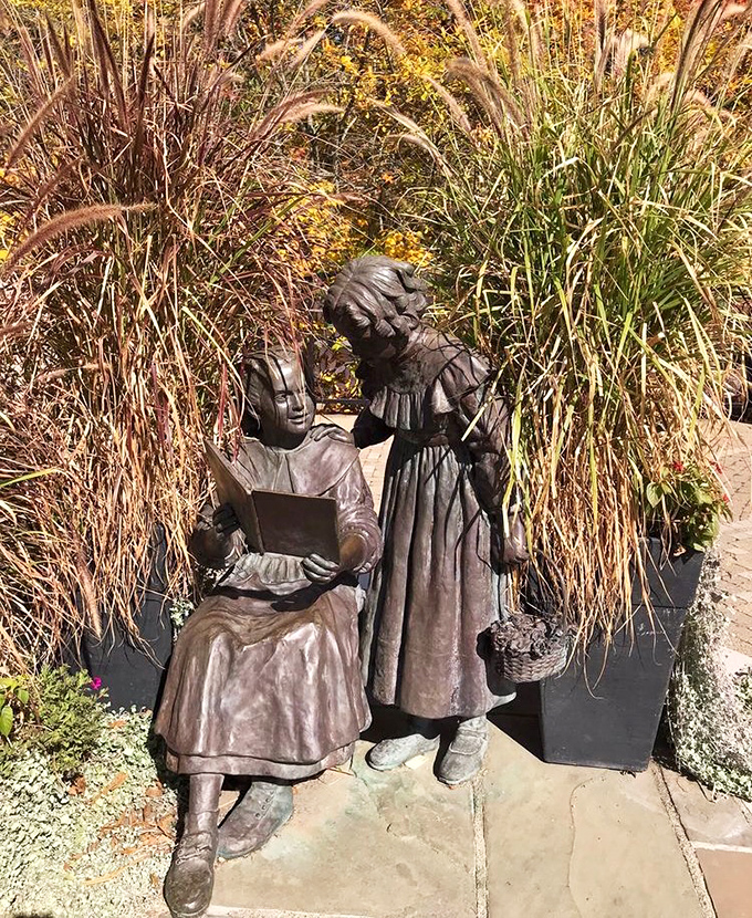 Bronze sisters share a quiet moment amid swaying ornamental grasses. This sculpture captures the spirit of the Innis sisters who gifted this paradise.