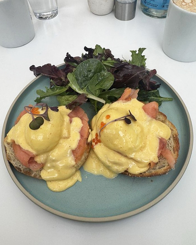Benedict perfection: silky hollandaise cascading over smoked salmon like a golden waterfall, with microgreens standing by for moral support.