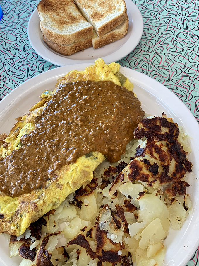 Behold the legendary Southern Omelet in its gravy-cascading glory. Those perfectly crisped hash browns aren't just a side&mdash;they're an essential supporting character.