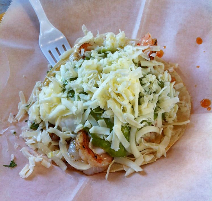 This shrimp taco isn't just food; it's an engineering marvel of perfectly balanced textures where seafood meets fresh crunch under an avalanche of cheese.