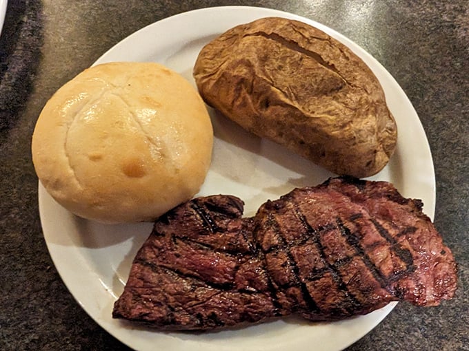 This isn't just a steak; it's a masterpiece of simplicity&mdash;perfectly grilled beef alongside a fluffy baked potato and fresh roll. Sometimes the classics need no improvement.