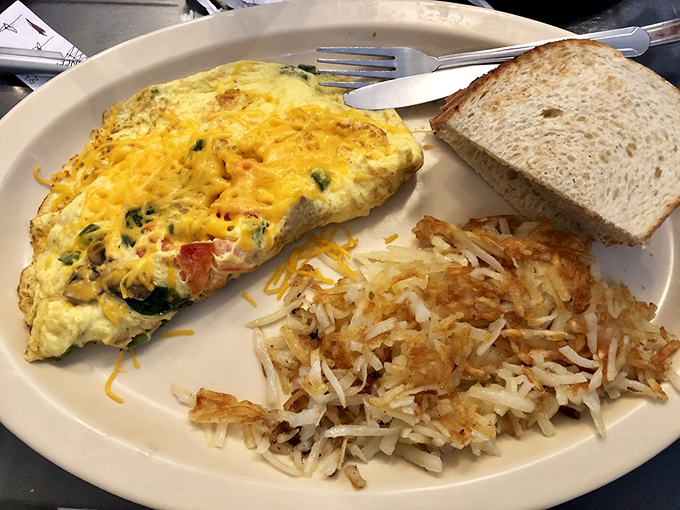 A perfectly executed veggie omelet that proves vegetables can party before noon, especially with those crispy hash browns.