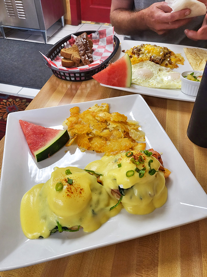 Eggs Benedict done right &ndash; golden hollandaise cascading over perfectly poached eggs, with crispy hash browns and fresh watermelon providing that sweet-savory balance.