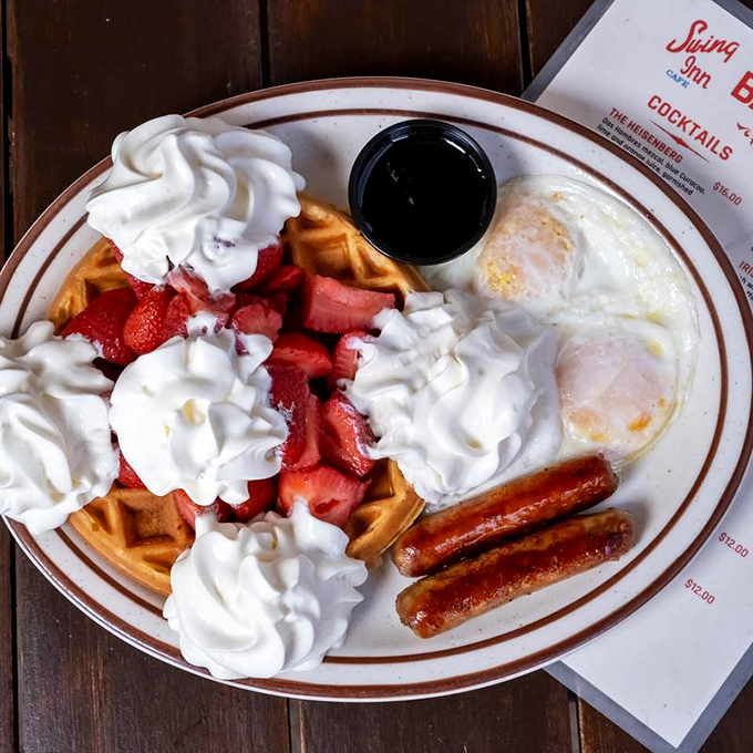 Breakfast nirvana: golden waffles crowned with strawberries and whipped cream, flanked by eggs and sausage &ndash; the breakfast equivalent of winning the lottery.