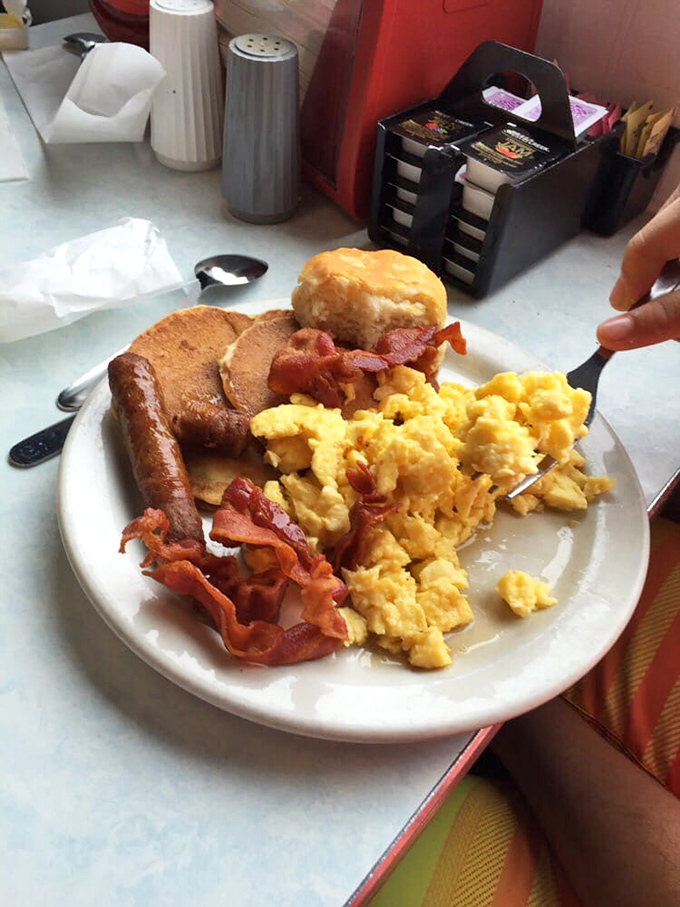 A plate that answers the eternal question: "Why choose?" Scrambled eggs, crispy bacon, sausage, and a fluffy biscuit create the breakfast quartet your stomach has been requesting.